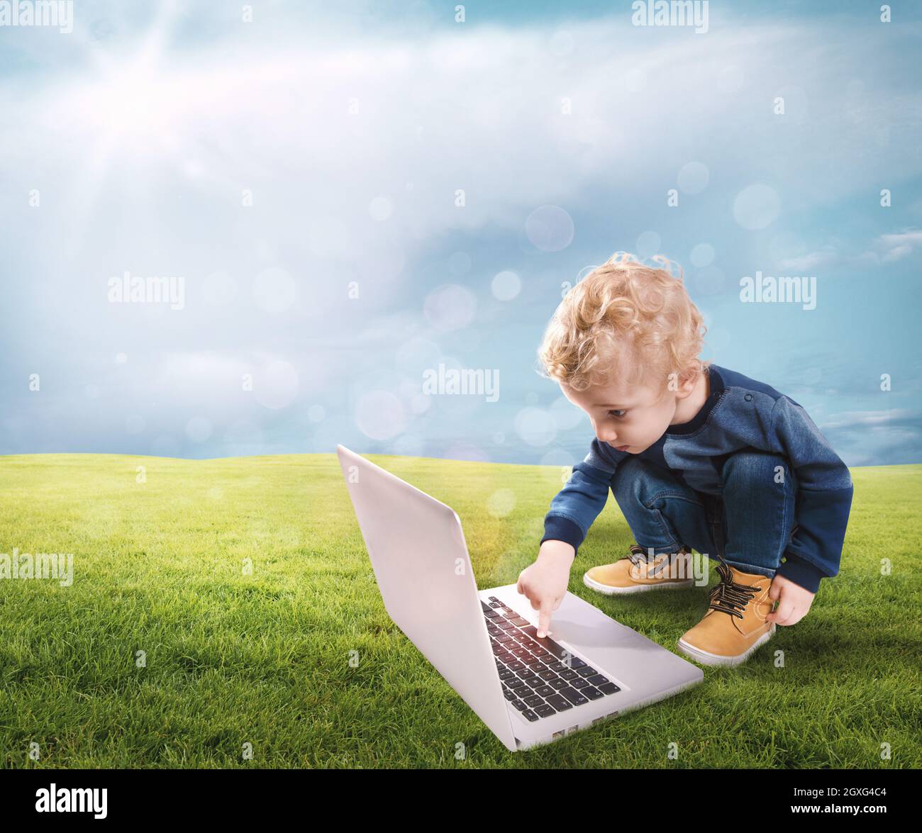 Child touching computer keys on a green lawn Stock Photo - Alamy