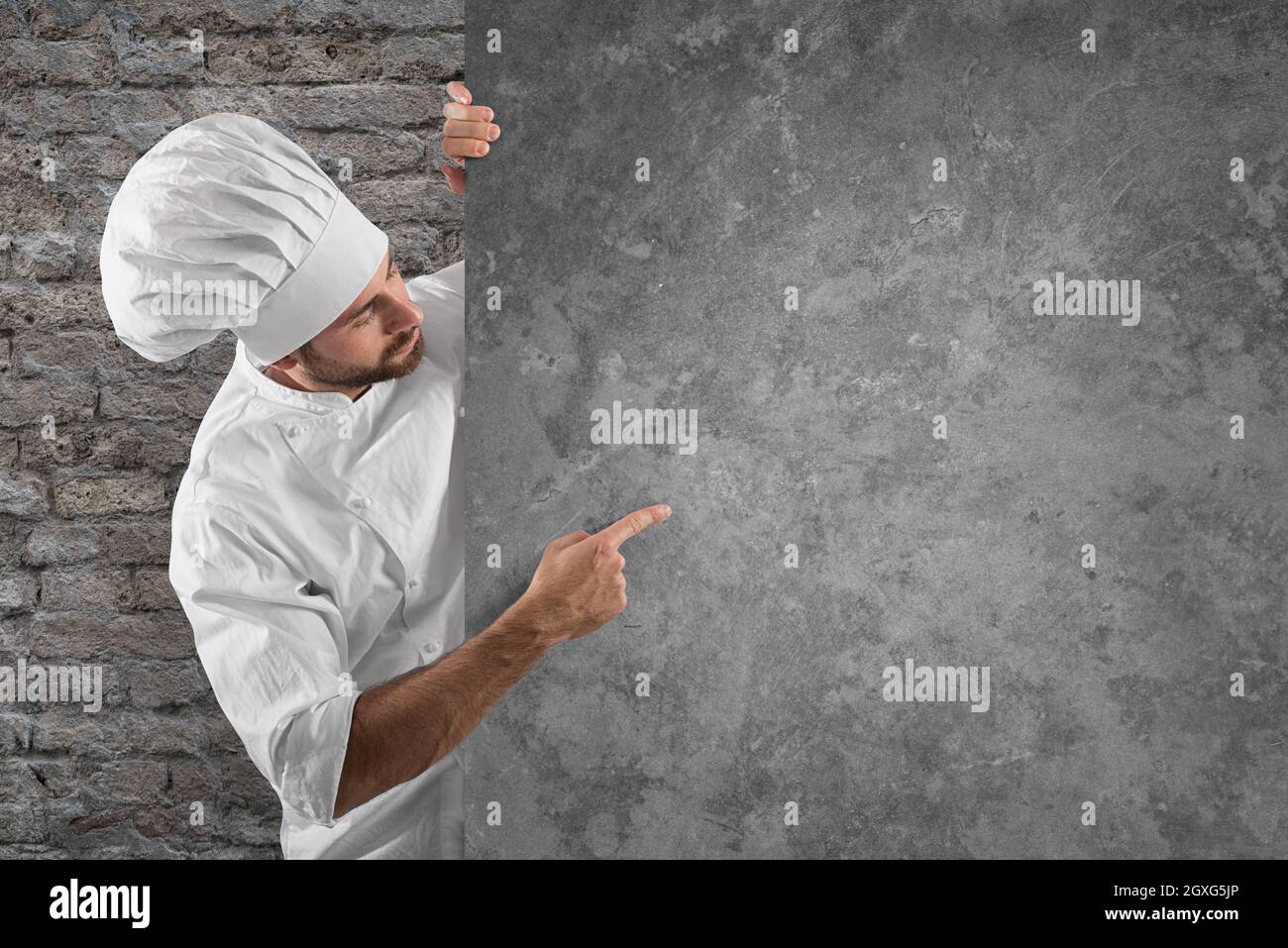 Chef showing and indicates his menu on a grey billboard Stock Photo - Alamy