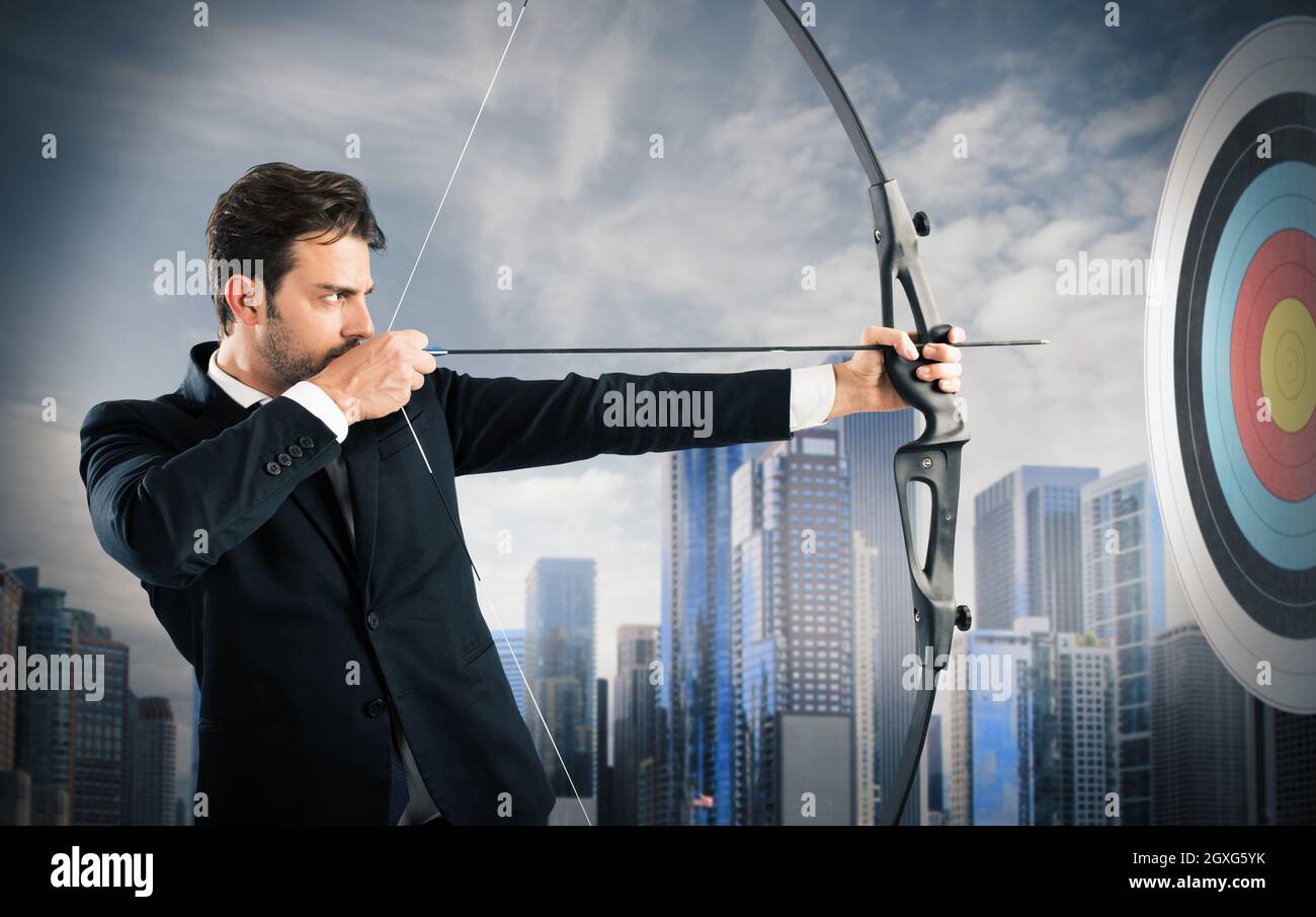 Businessman with bow and arrow aiming a target Stock Photo - Alamy