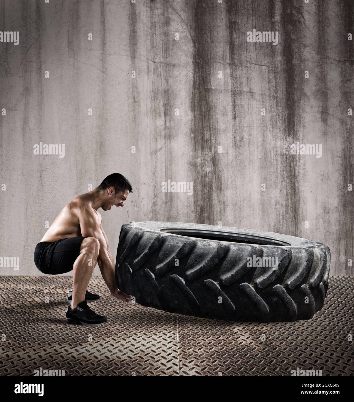 Athletic muscular man raises a big tire Stock Photo - Alamy
