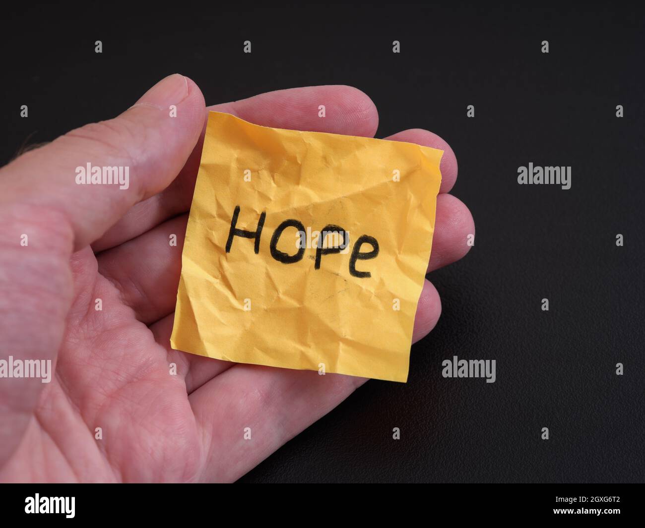 A man holding a piece of yellow paper with the word Hope on it in his ...