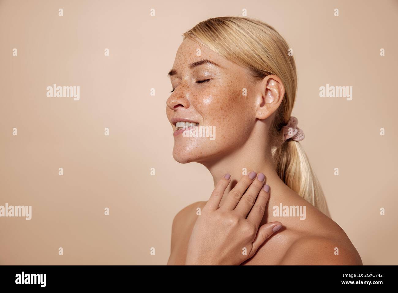 Side view of smiling woman with freckles standing with closed eyes ...
