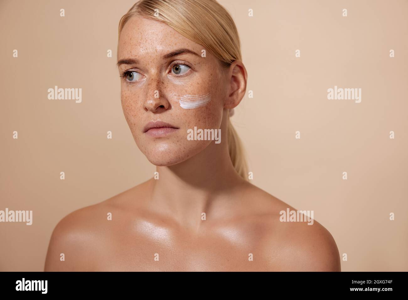 Studio portrait of a young woman with a cream on her face looking away ...