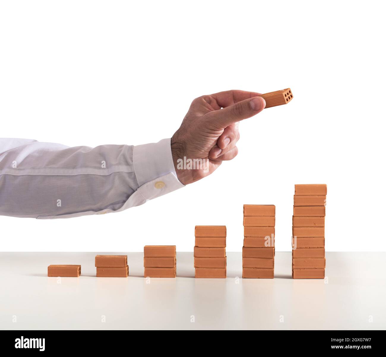 Businessman puts a brick on a static made bricks. Concept of growing ...