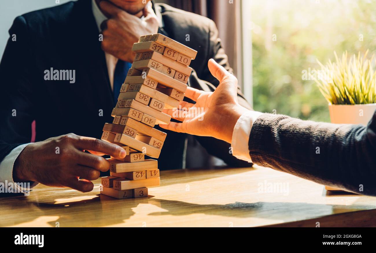 Business man strategy risk pulling block wood tower and have one ...