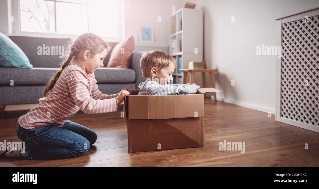 Cute children playing with cardboard box in living room. Concept of ...