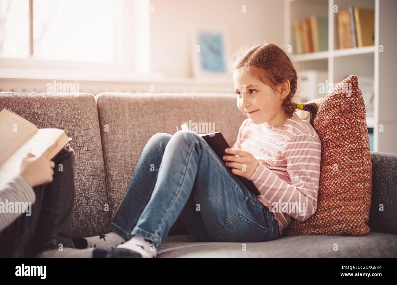 Pretty girl have a rest on the cozy couch with interesting book ...