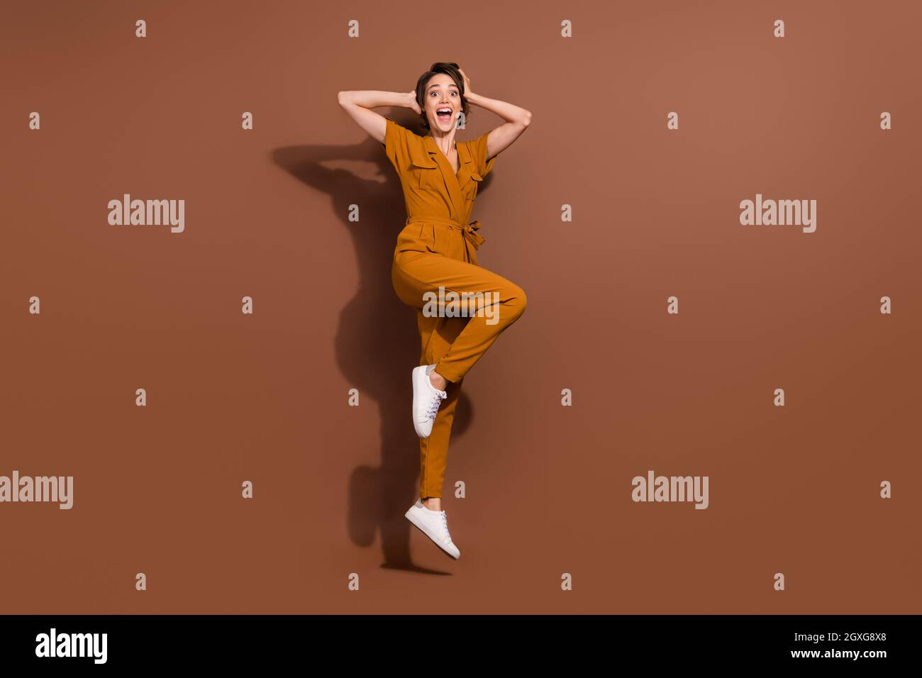 Full body photo of amazed shocked young woman jump hold hands head news ...