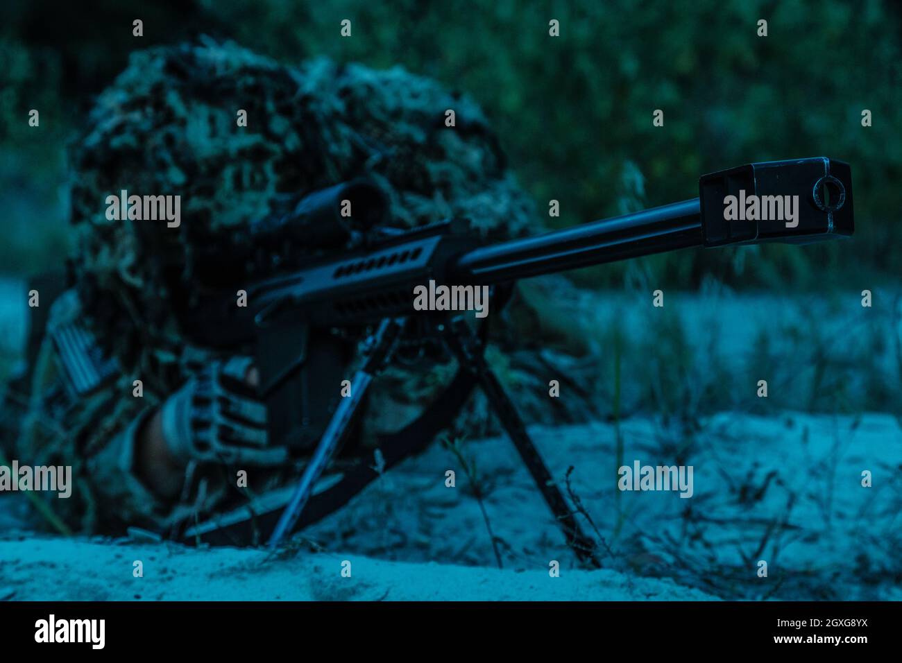 Army sniper with big rifle lying in wait in the forest at nighttime ...