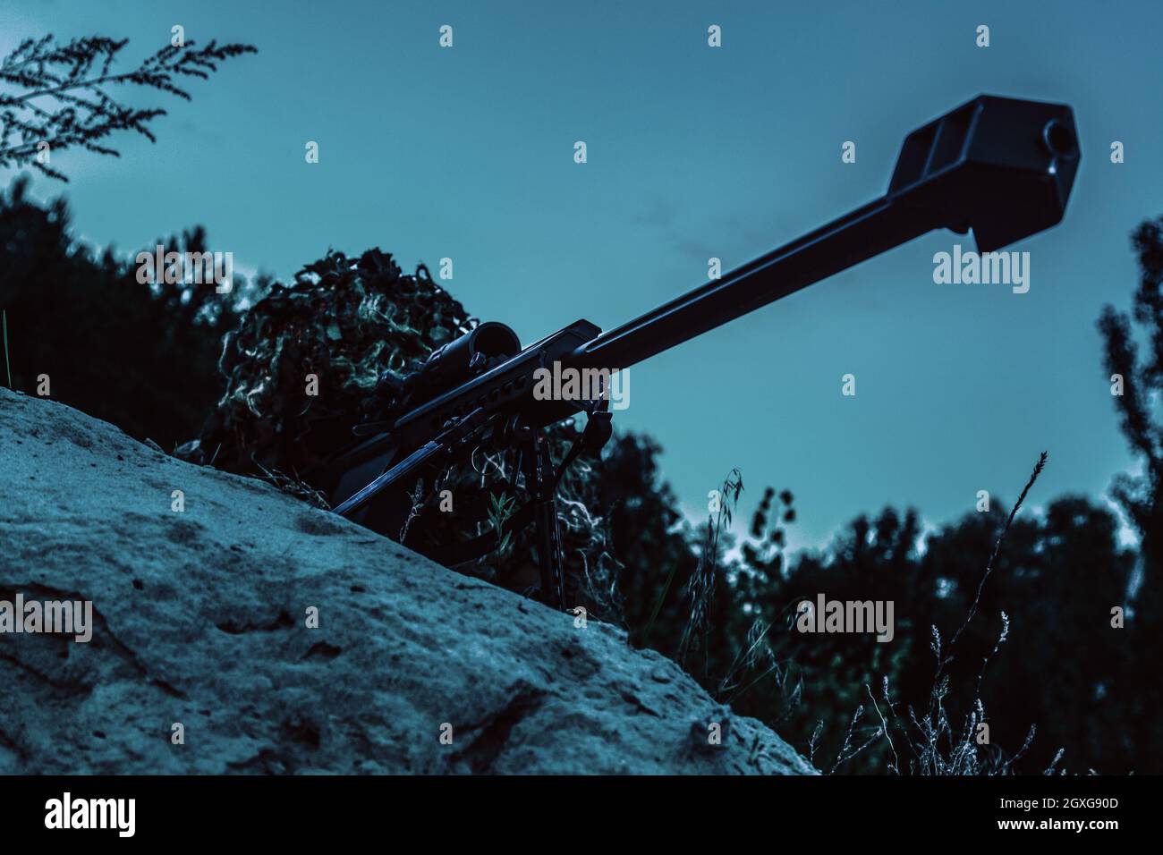 Army sniper with big rifle lying in wait in the forest at nighttime ...