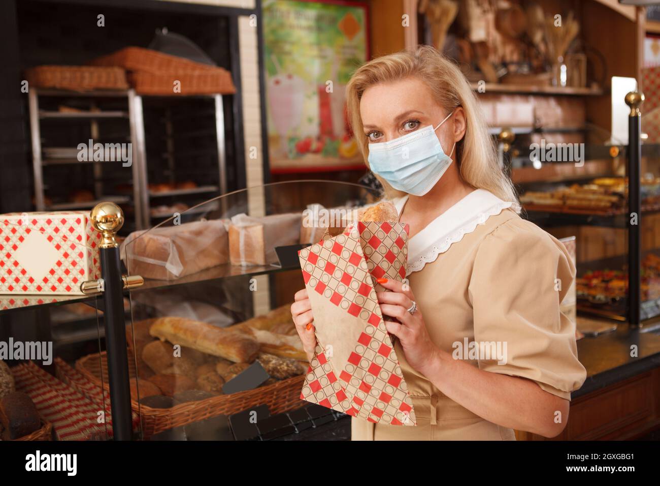 Female customer wering medical face mask, buying bread at the bakery ...