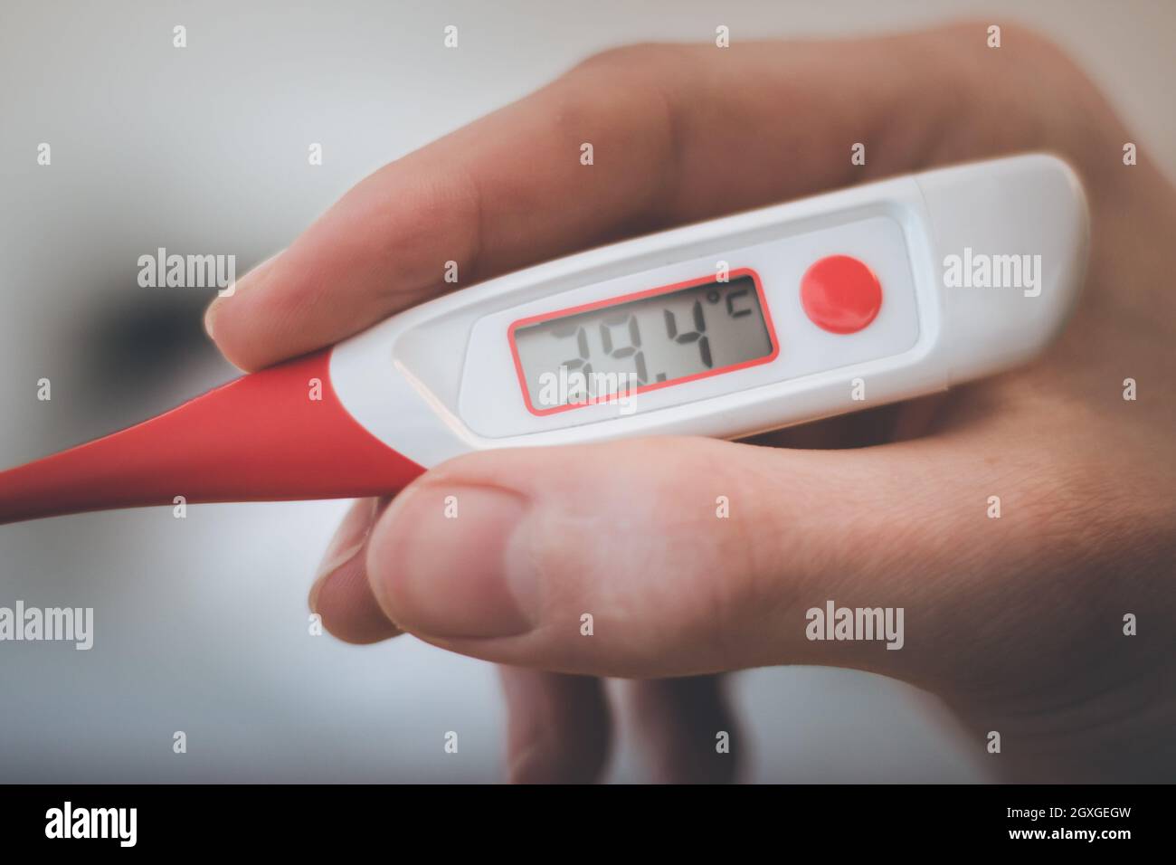 Man holds a red fever thermometer with 39 degrees Celsius in his hand ...