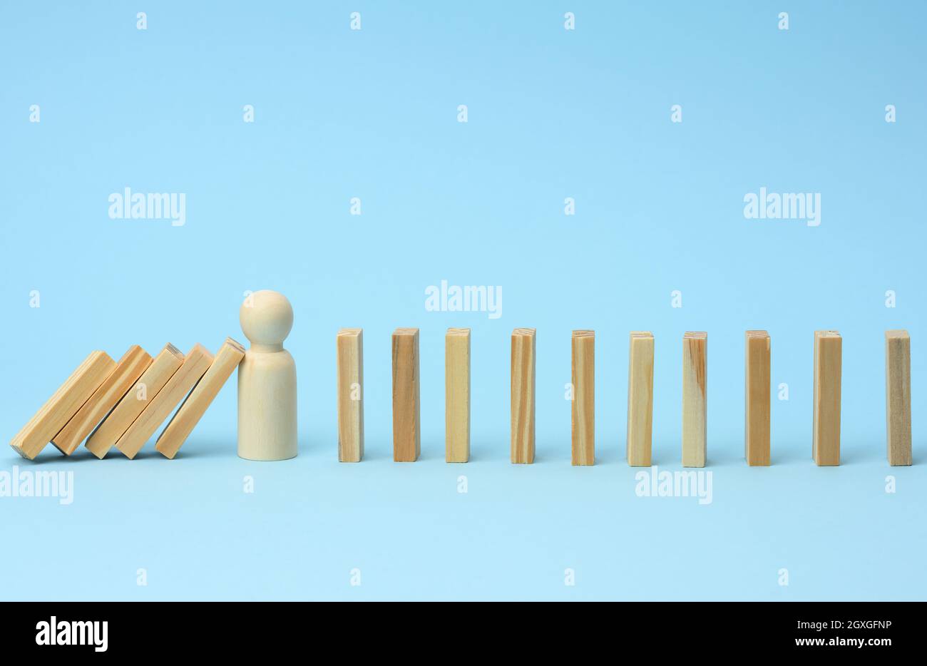 wooden model of a man stops falling of wooden bars on a light blue ...