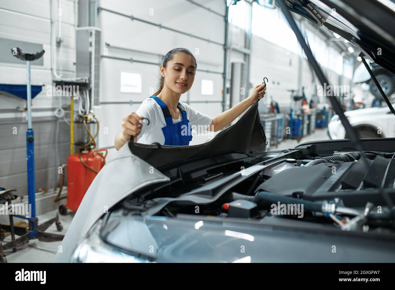 Female mechanic stands at the hood, car service. Vehicle repairing ...