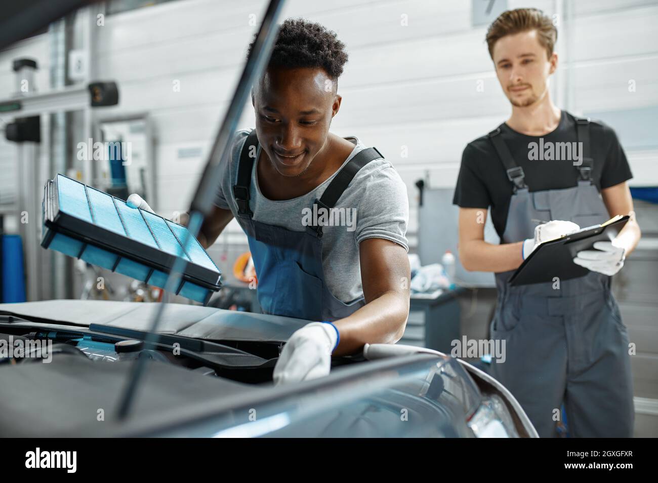 Two male workers repairs engine, car service. Vehicle repairing garage ...