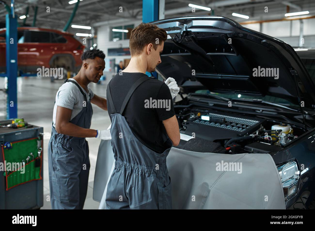 Two male workers repairs engine, car service. Vehicle repairing garage ...