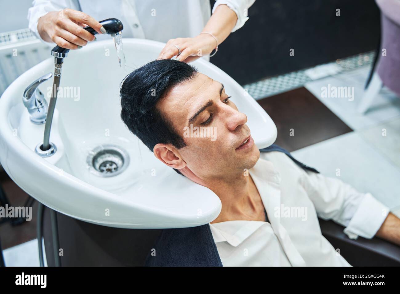 Beautician washing man hair in wash sink Stock Photo - Alamy