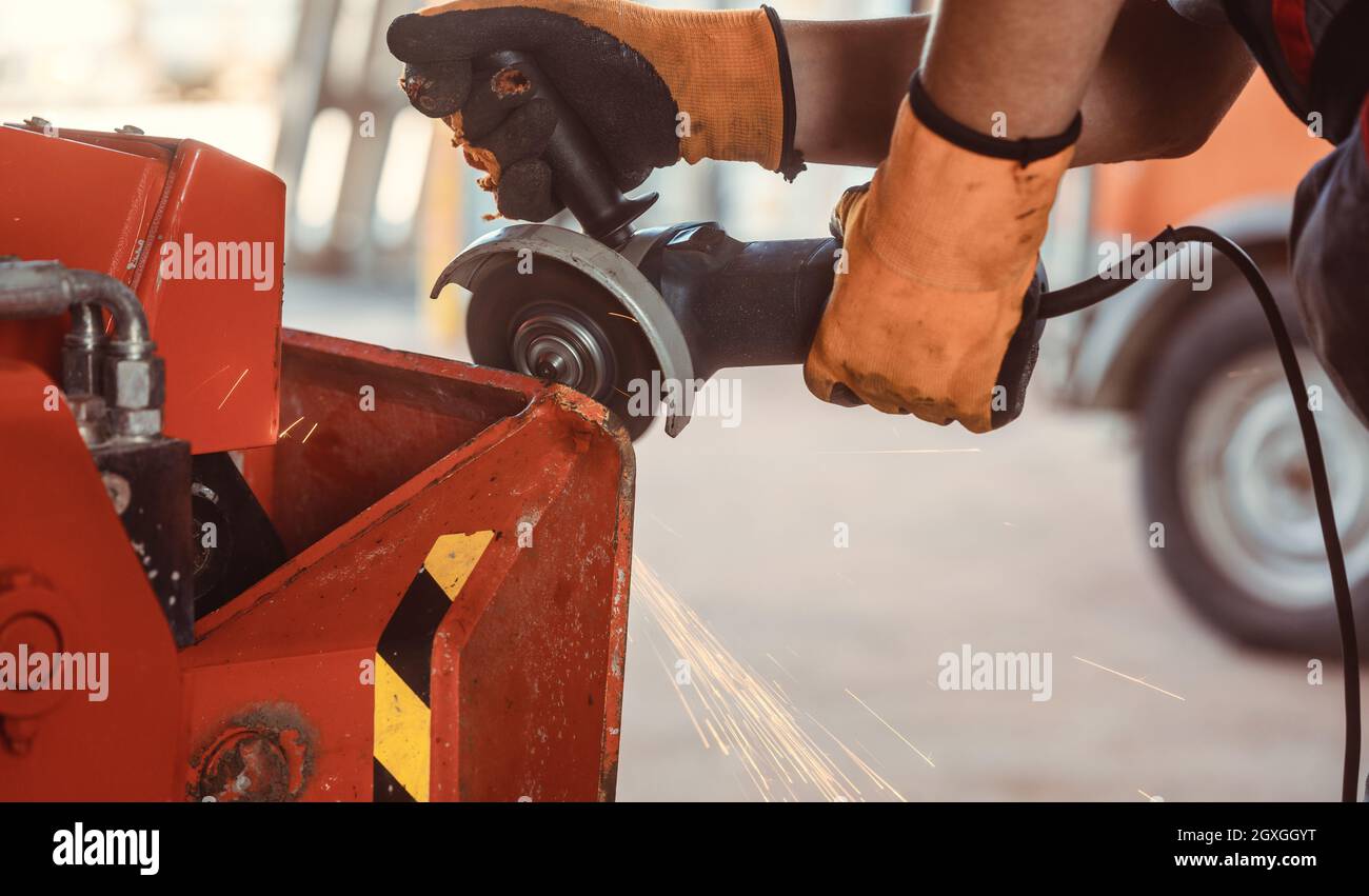 Technician with disk grinder working on farm machine, sparks fly Stock ...
