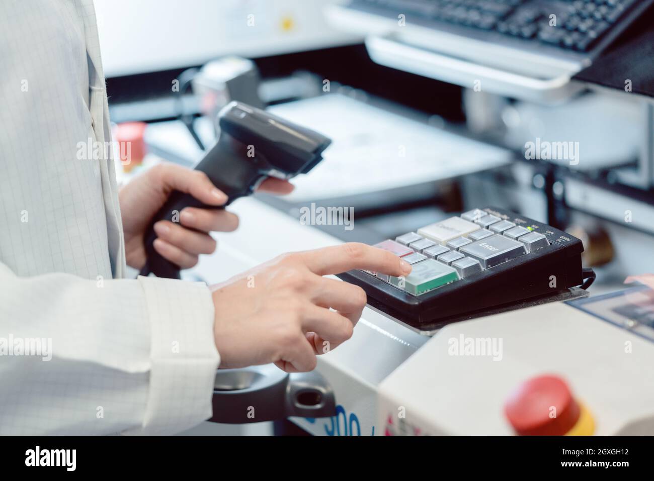 Factory worker pressing the OK button on a machine to start production ...
