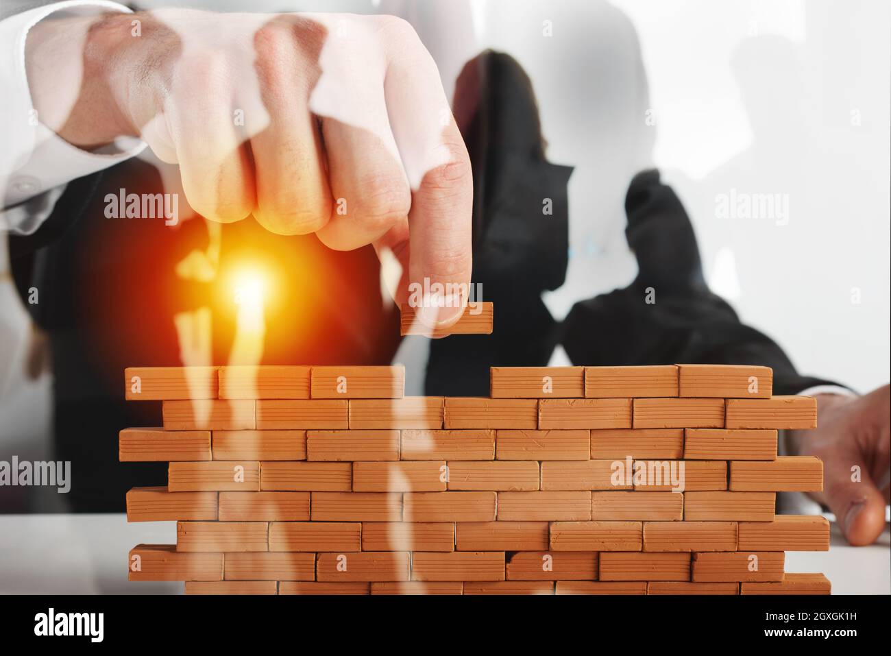 Businessman puts a brick to build a big wall. Concept of new business ...