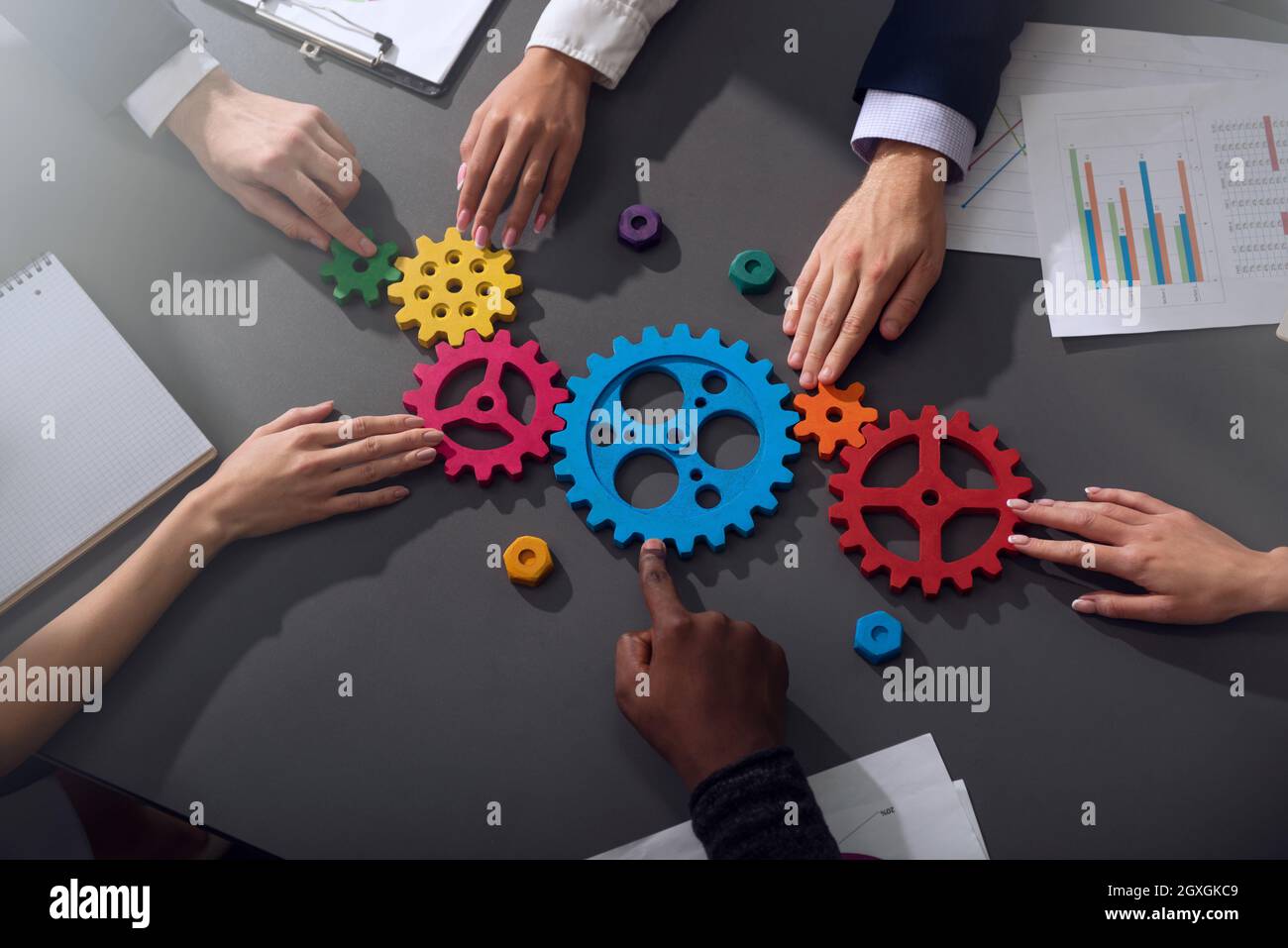 Teamwork of businesspeople work together and combine pieces of gears ...