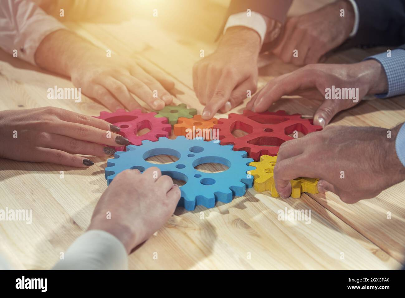 Teamwork of businesspeople work together and combine pieces of gears ...