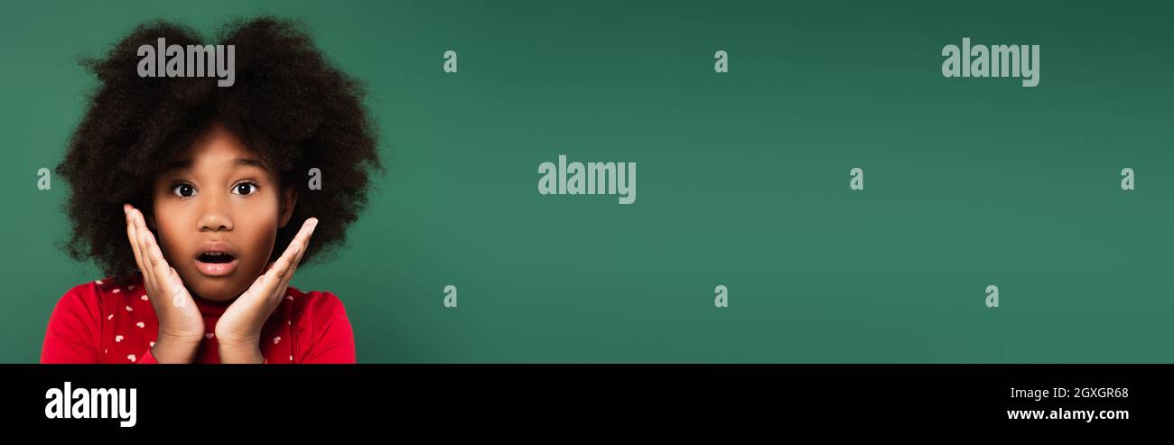 Astonished african american girl looking at camera isolated on green ...