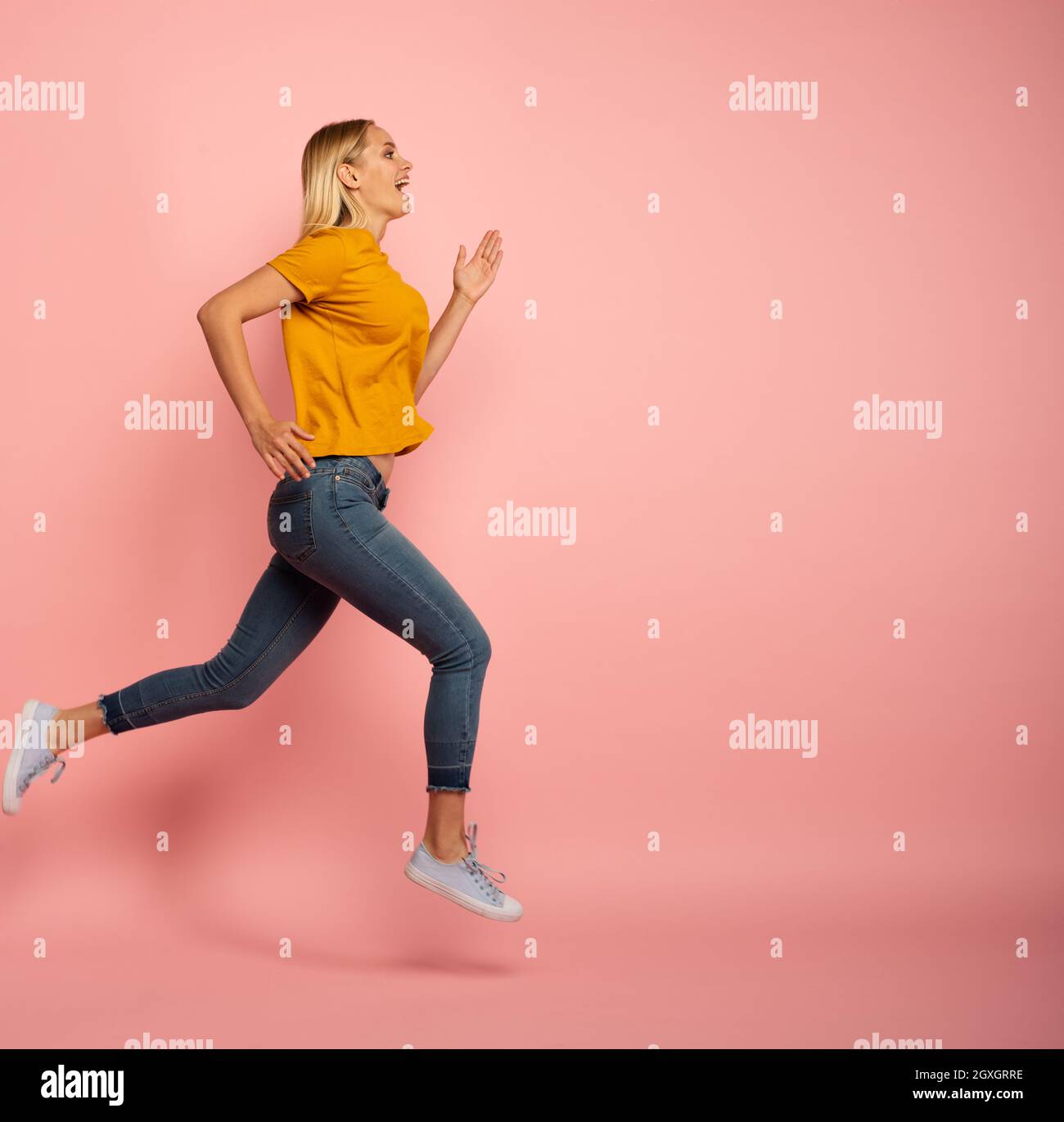 Blonde girl runs fast. Concept of energy and vitality. Pink background ...