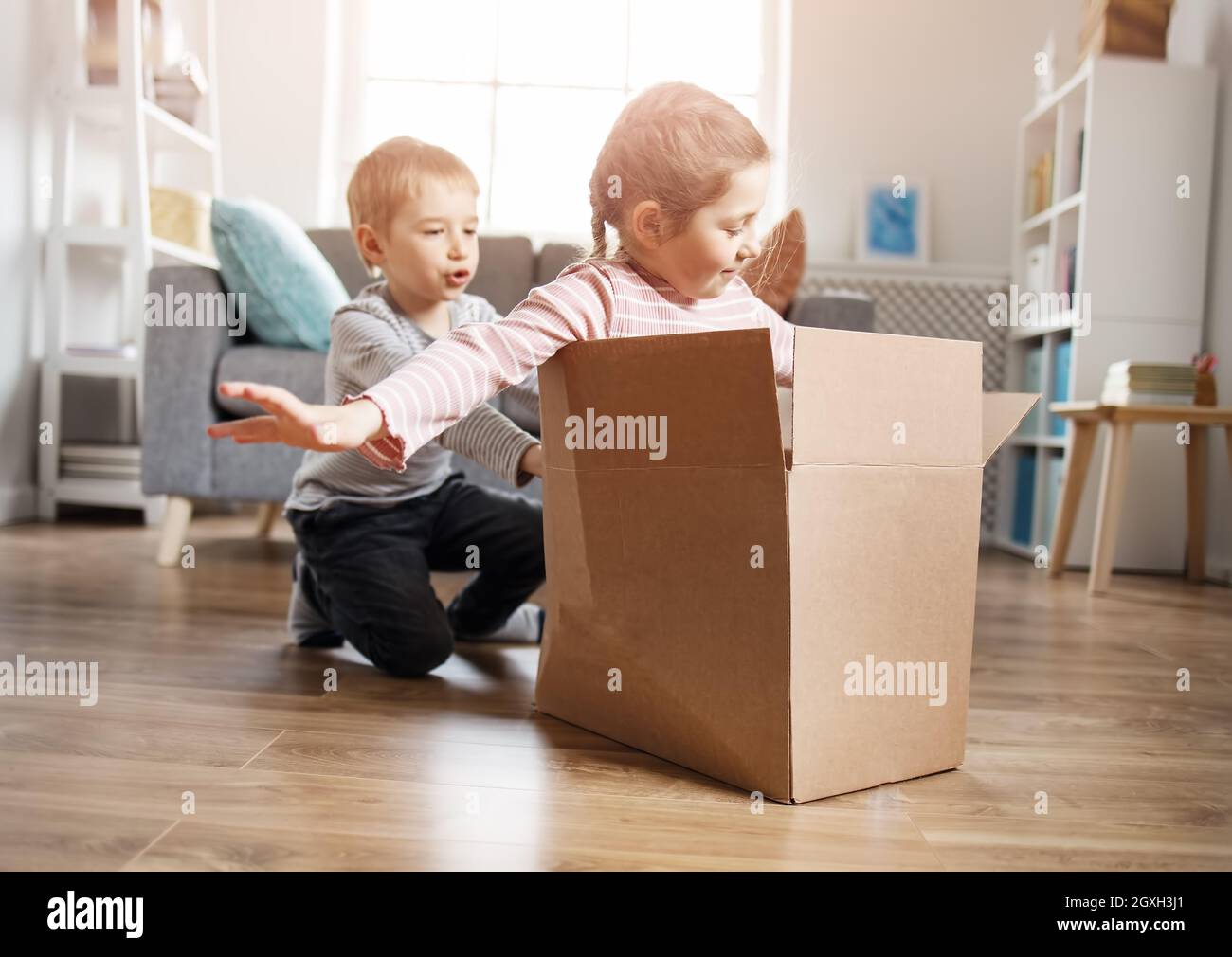 Cute children playing with cardboard box in living room. Concept of ...
