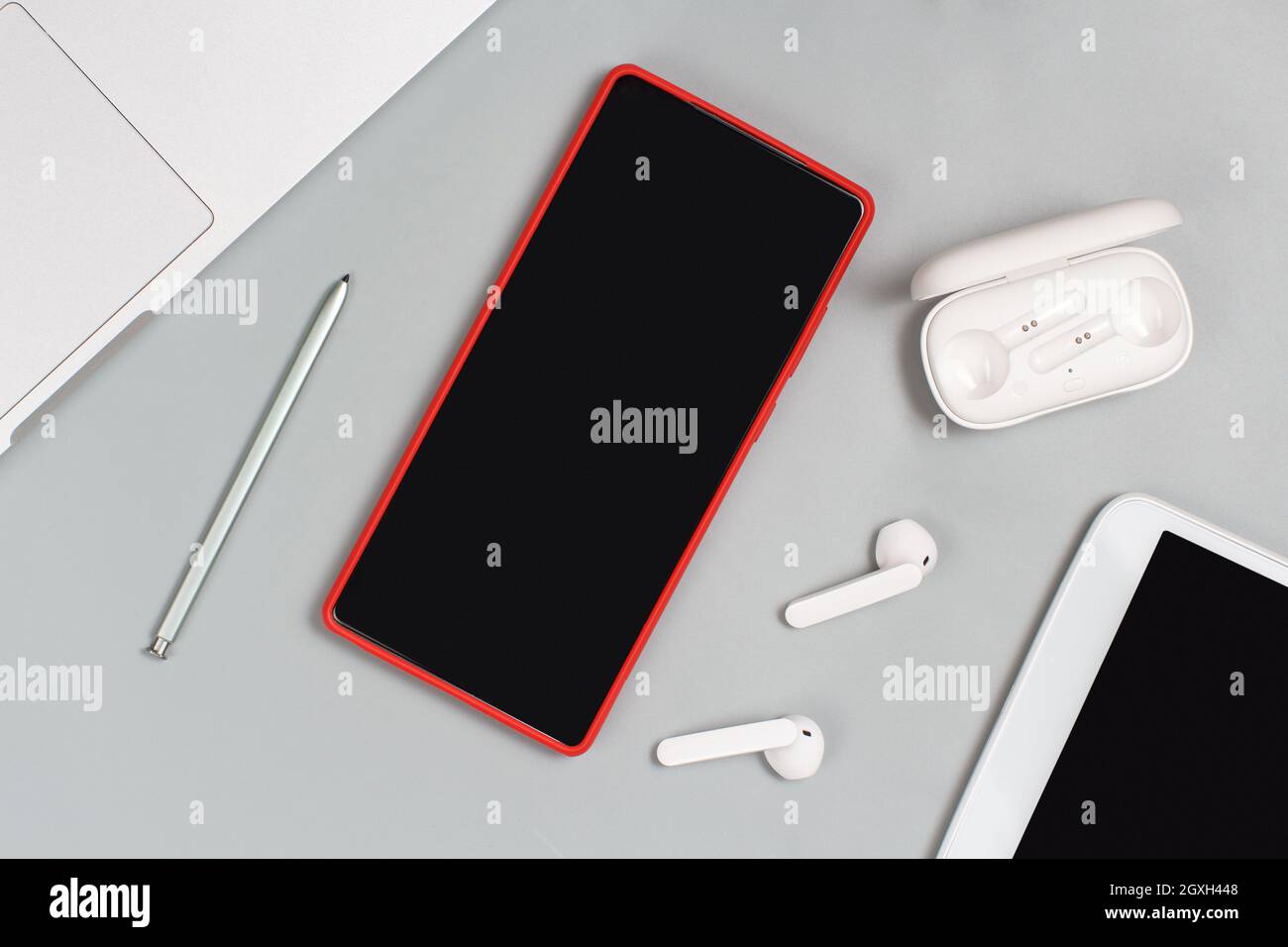 Red Mobile phone, earphones and tablet near laptop on white background ...