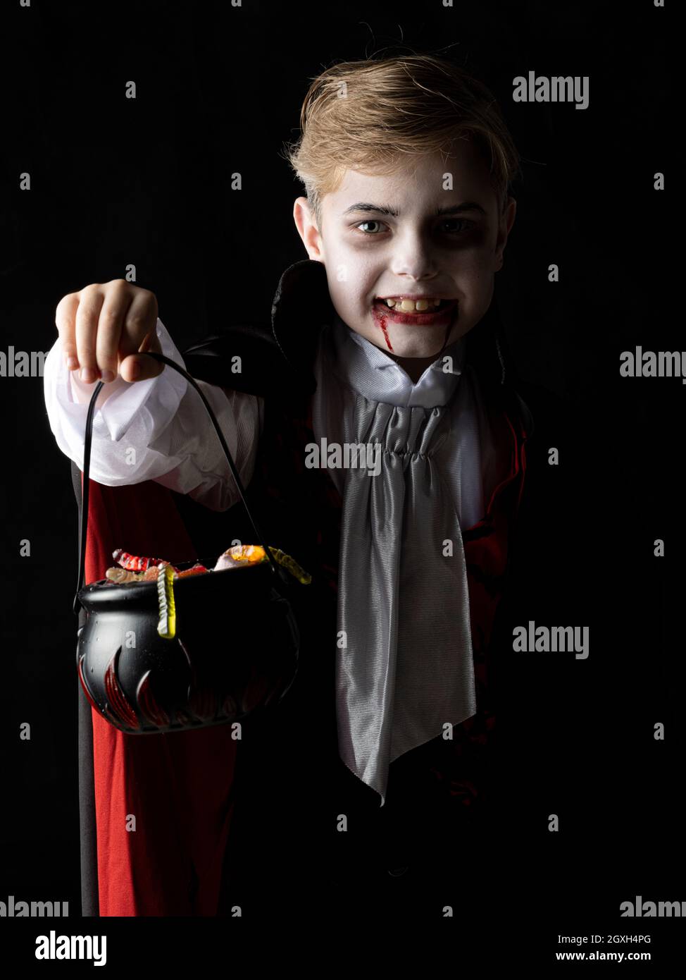 Boy with cauldron basket and worm sweets dressed as vampire for ...