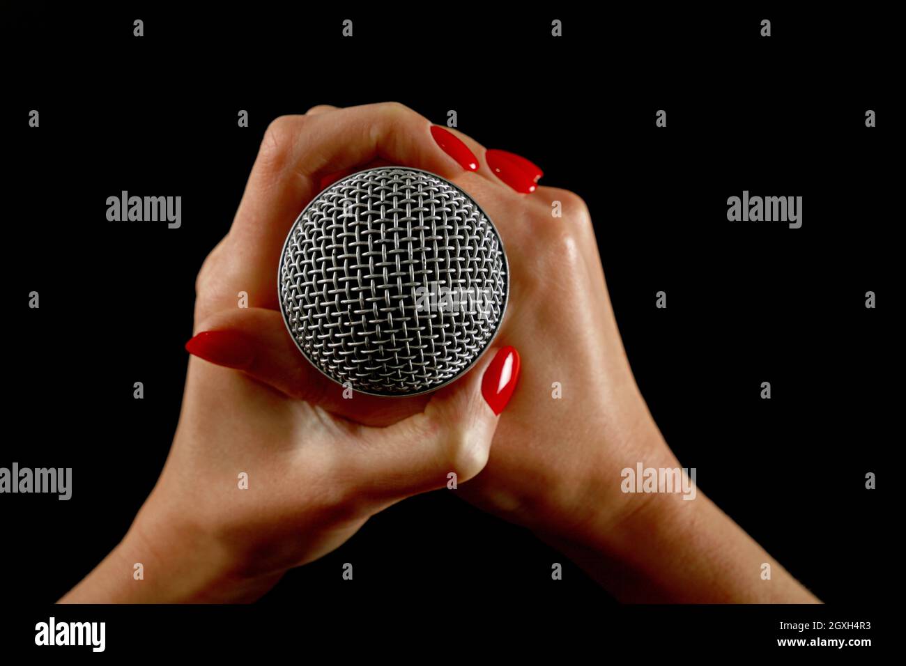 Woman holding microphone with two hands with red nails isolated on ...