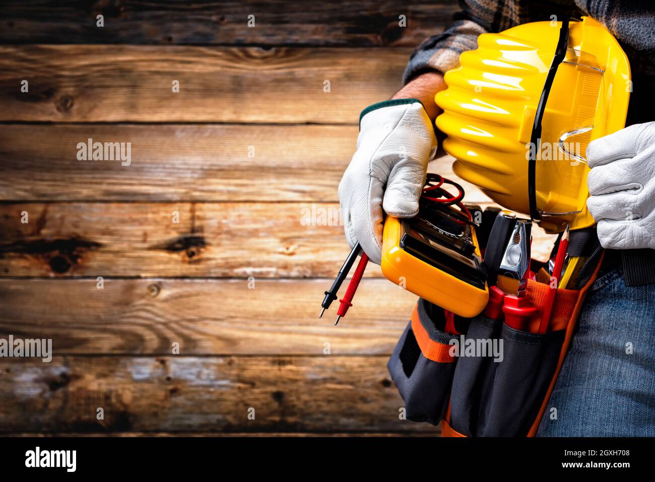 Electrician worker on vintage wooden background; holds the multimeter ...