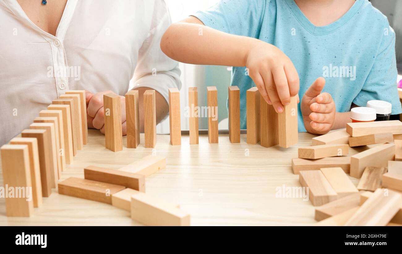 Little toddler boy putting wooden blocks or domino in long line ...