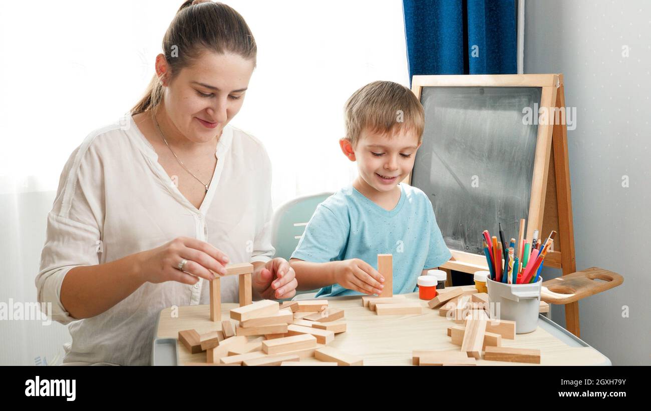 Little toddler boy with mother building tower from wooden blocks ...