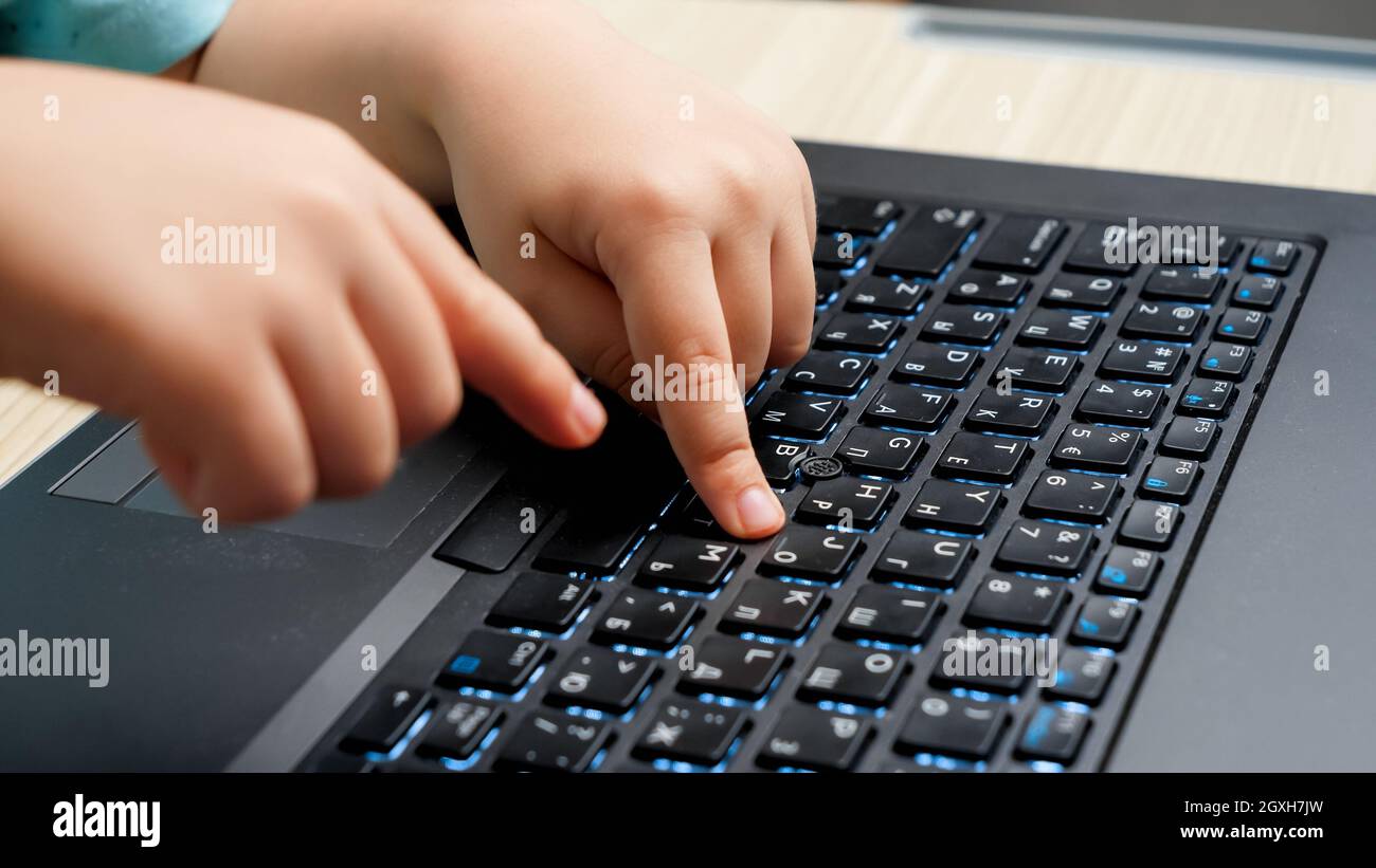 Closeup of child typing and pressing buttons on laptop keyboard. Smart ...