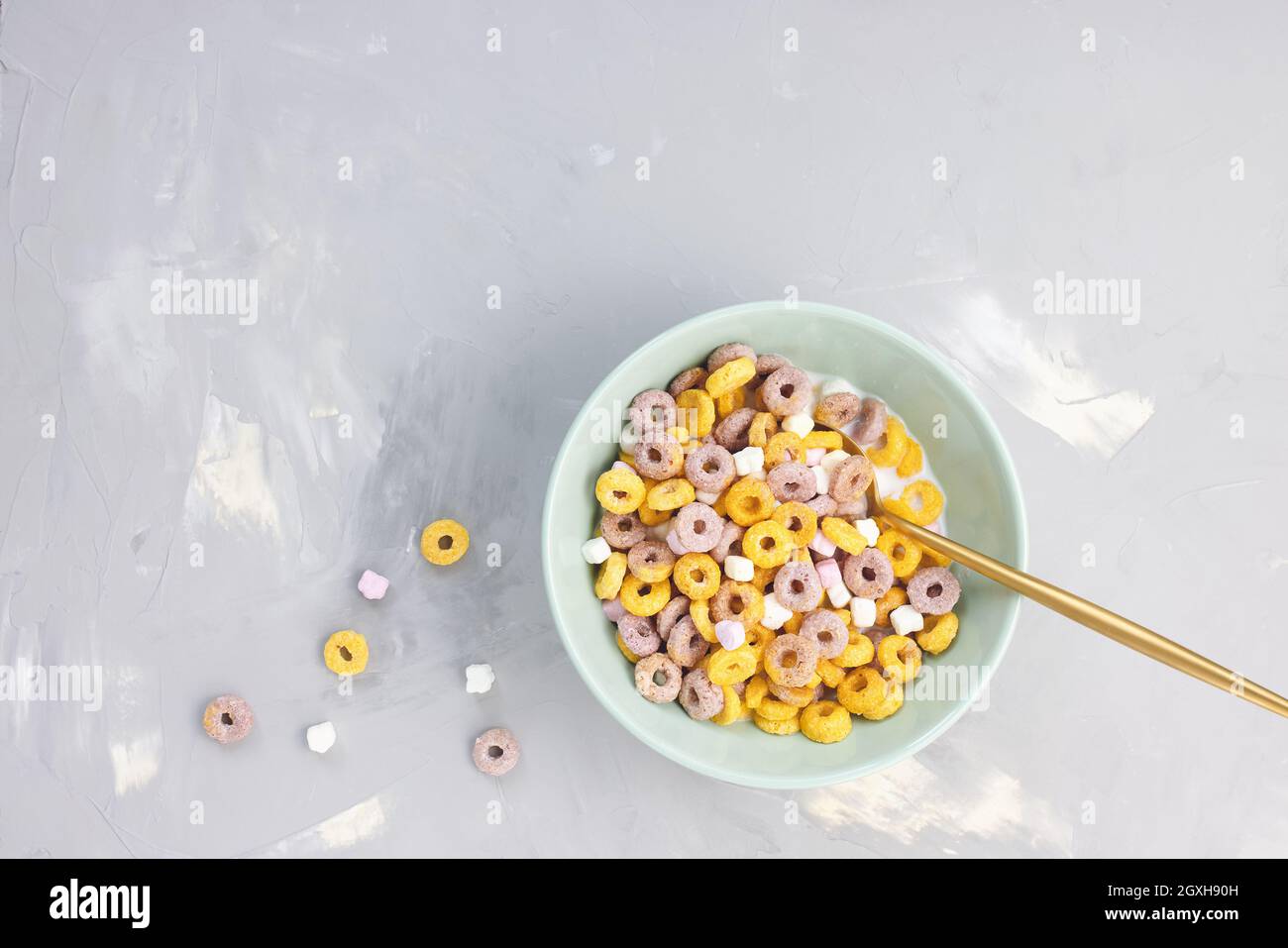 Multi colored cereal fruit loops and milk in a bow, golden spoon on ...