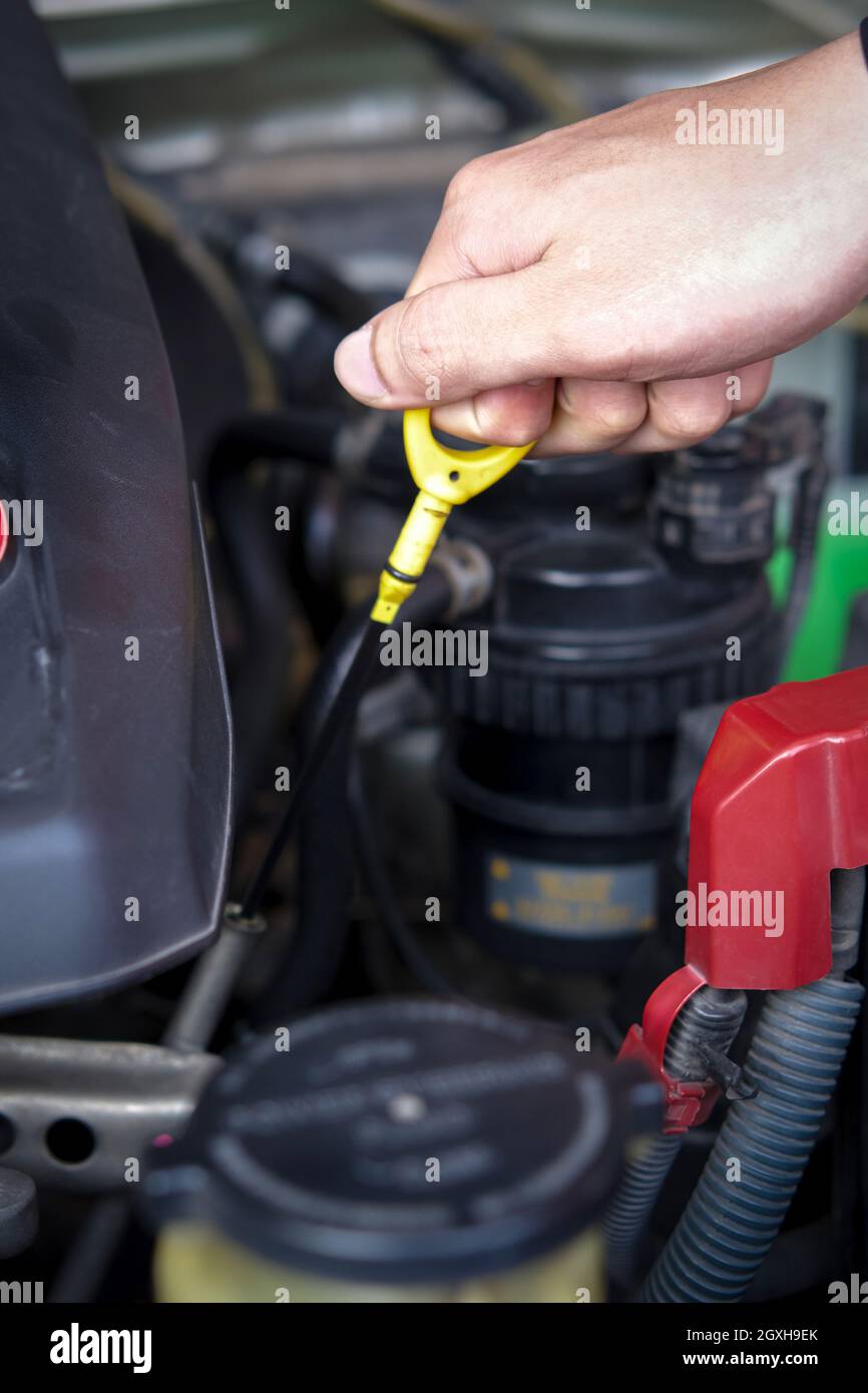 Closeup hand pulling the engine oil dipstick. Mechanic checking level motor oil in a car with ...
