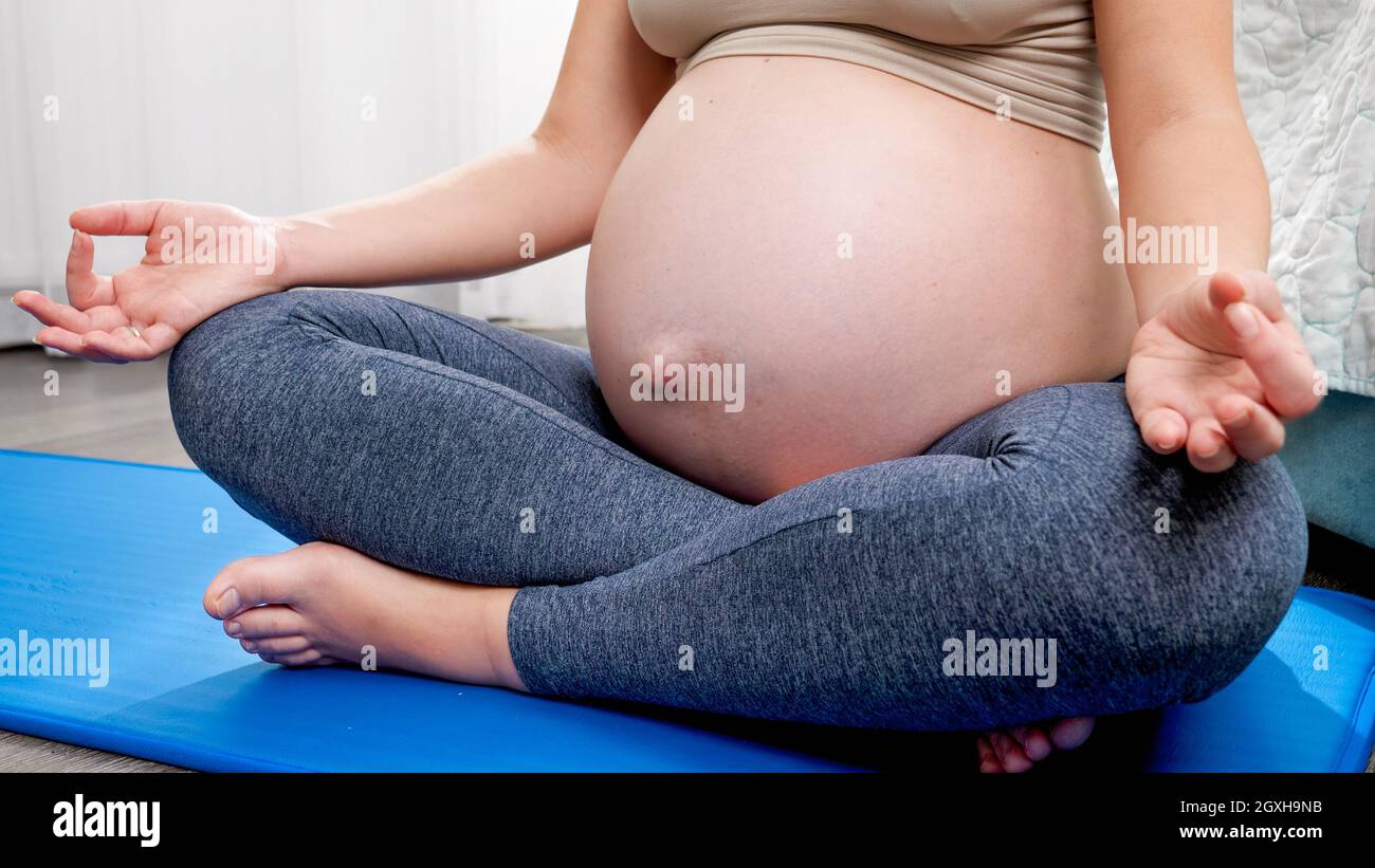 Closeup shot pregnant woman with big belly meditating and practicing ...