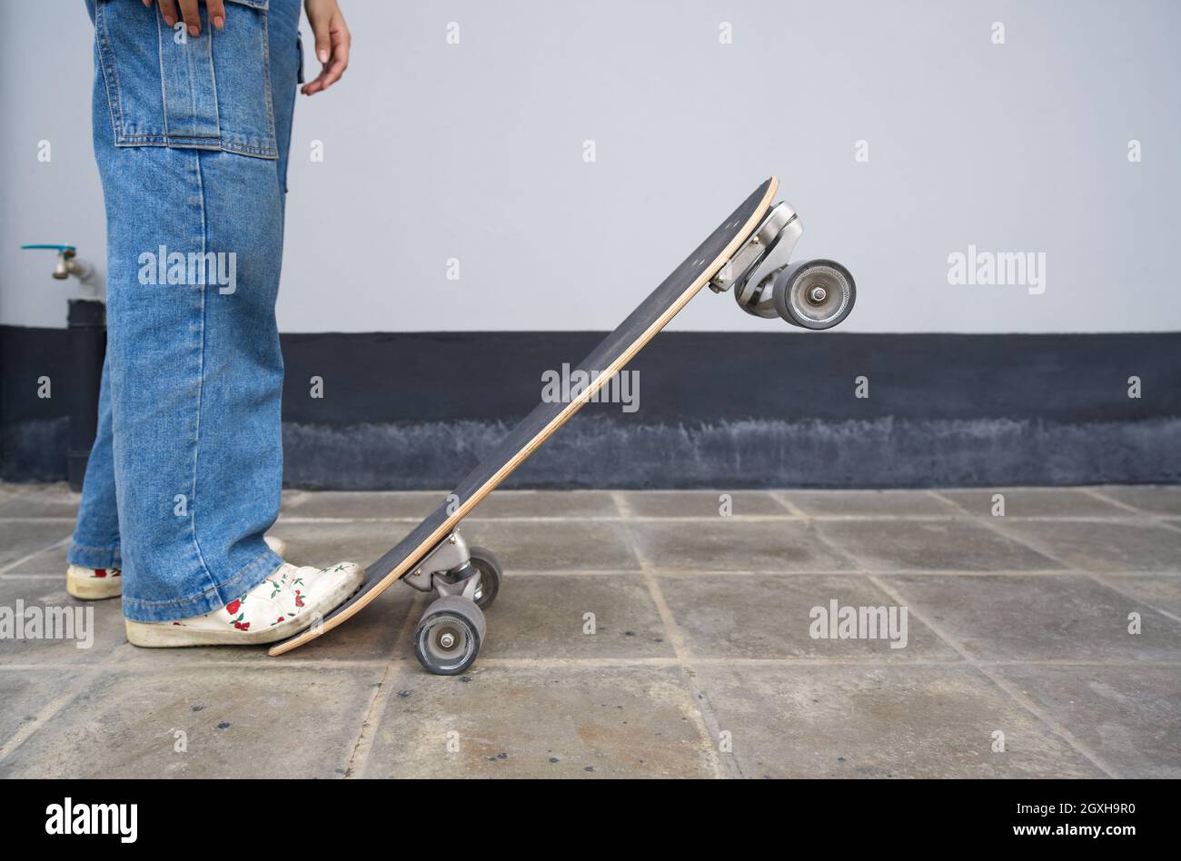 Closeup front foot push down at the tail of skateboard lifting the ...