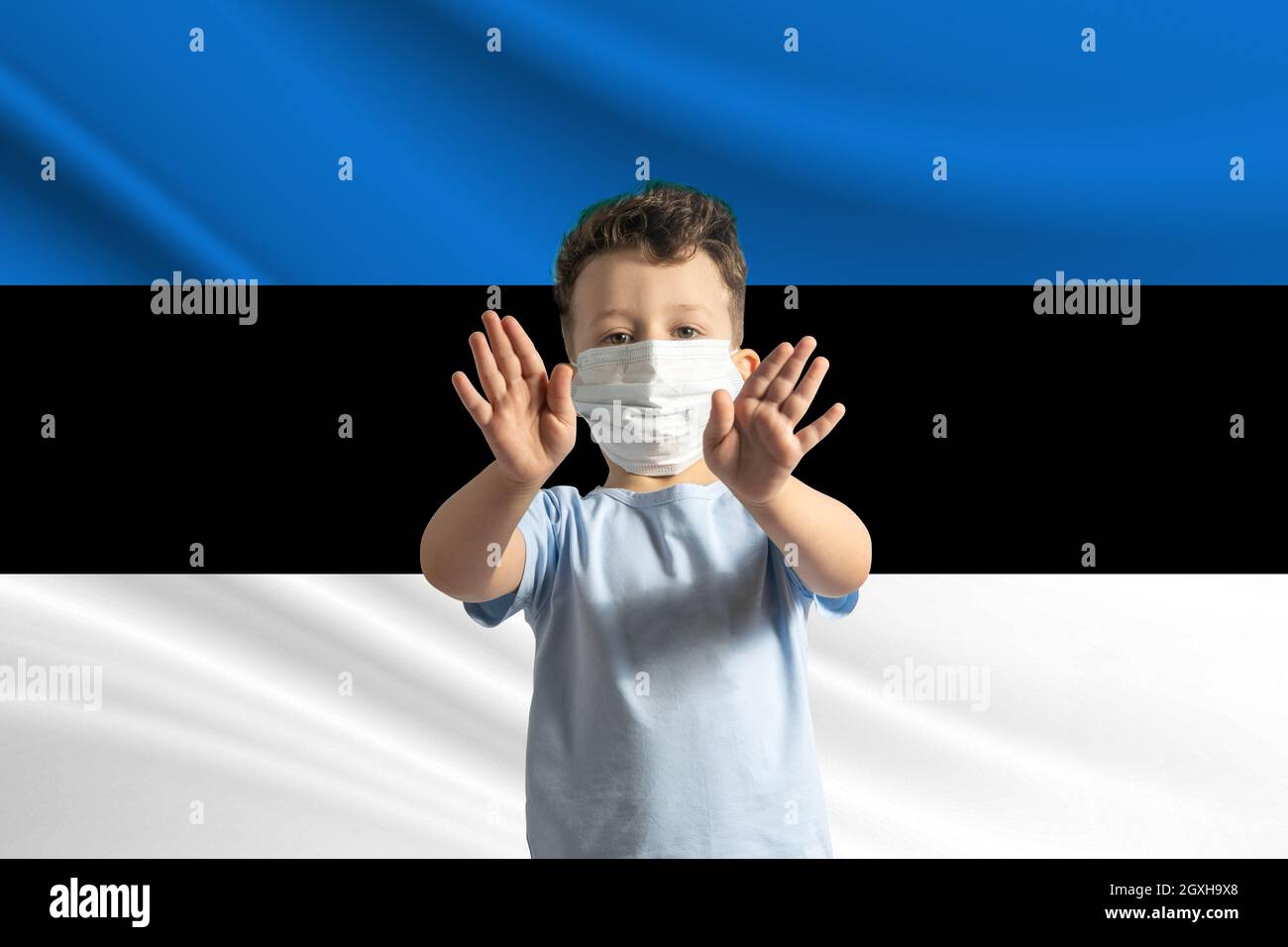 Little white boy in a protective mask on the background of the flag of ...