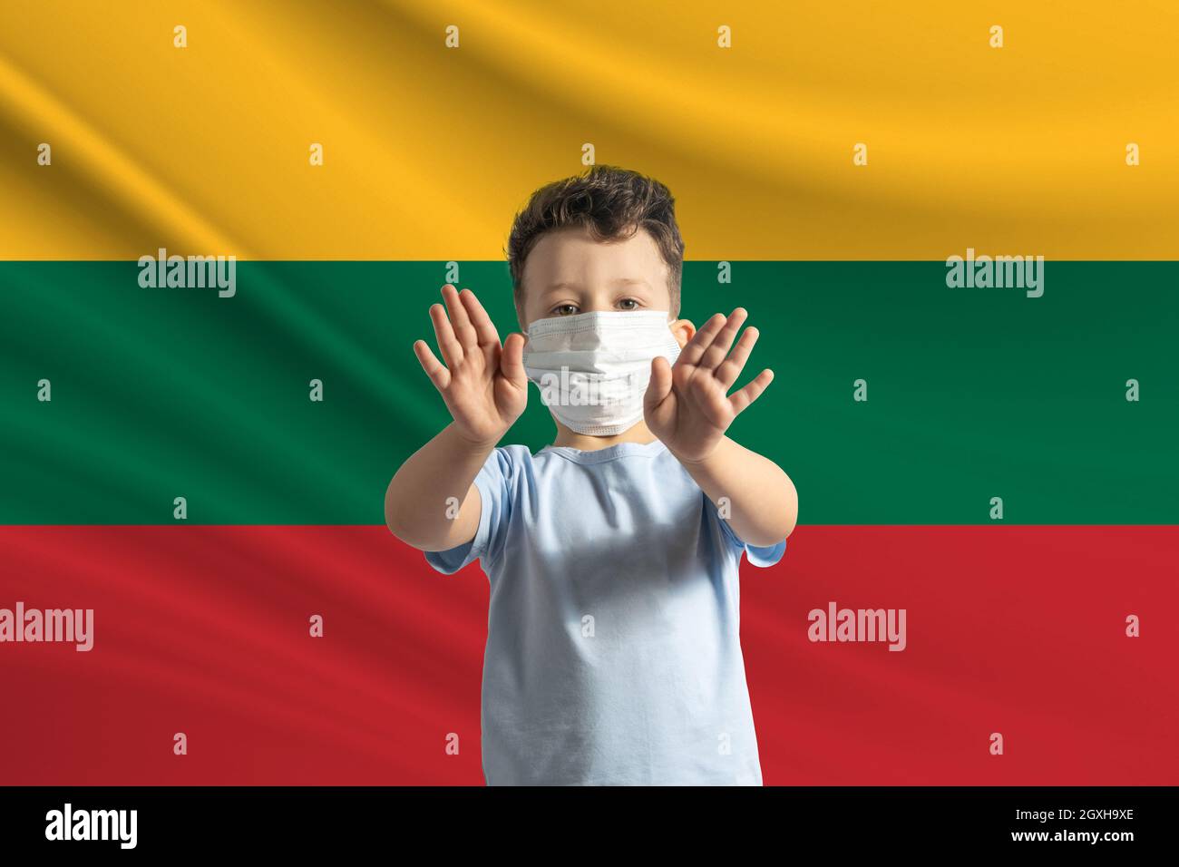 Little white boy in a protective mask on the background of the flag of ...