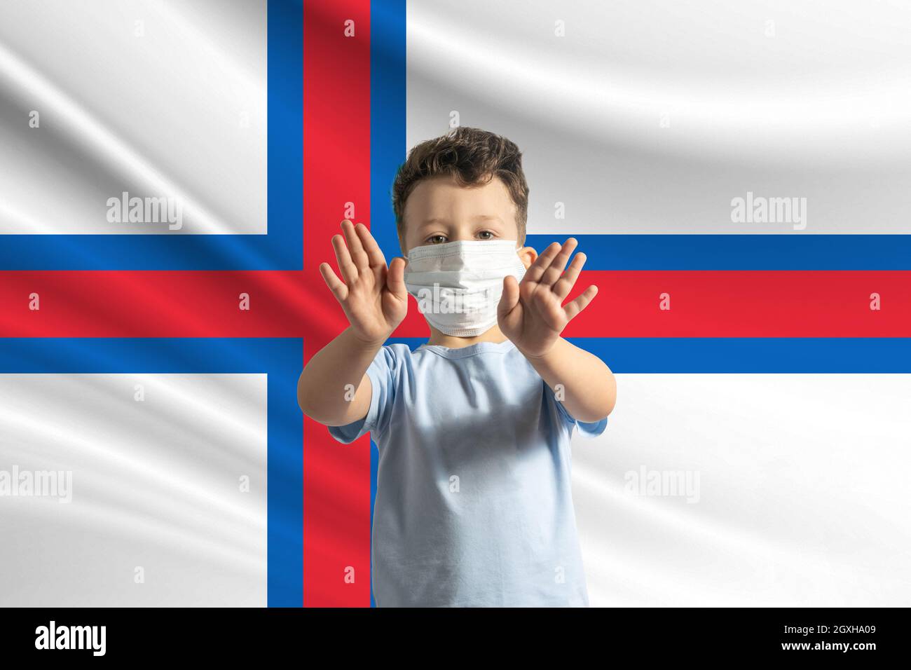 Little white boy in a protective mask on the background of the flag of ...