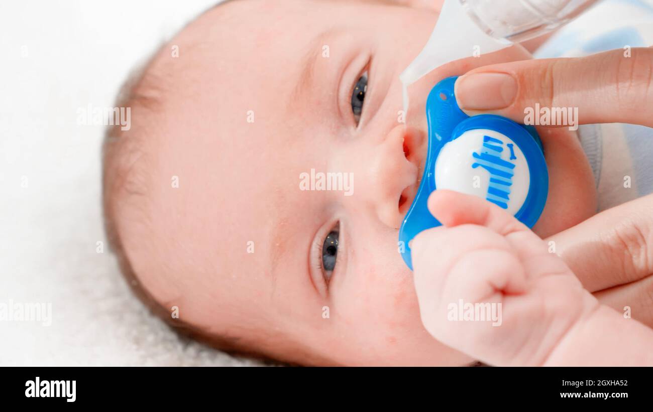Closeup of little newborn baby lying in crib while mother cleaning his ...