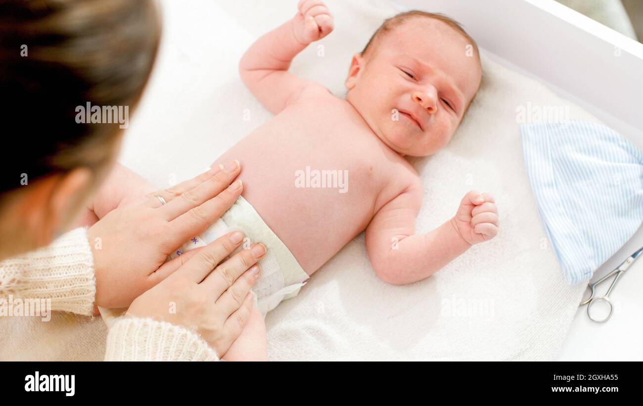 Young mother changing messy diapers to her newborn baby son Stock Photo ...