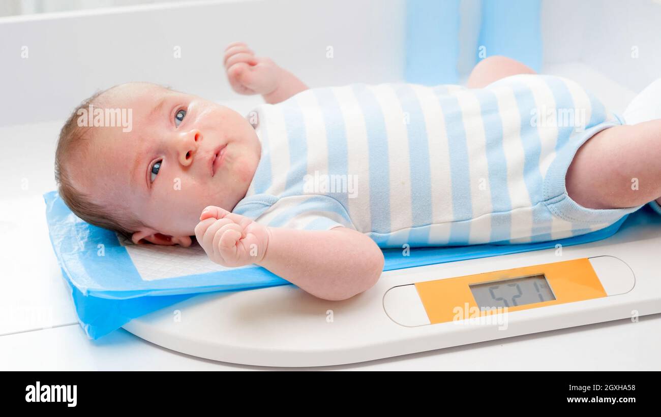 Caring mother weighing her little newborn baby son. Concept of babies ...