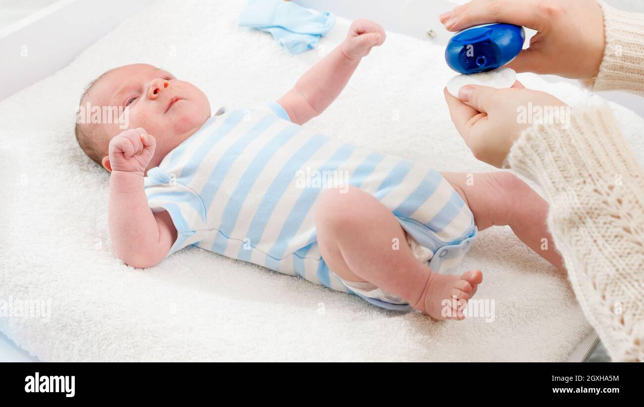 Young caring mother applying baby oil for moisturizing soft sking of ...