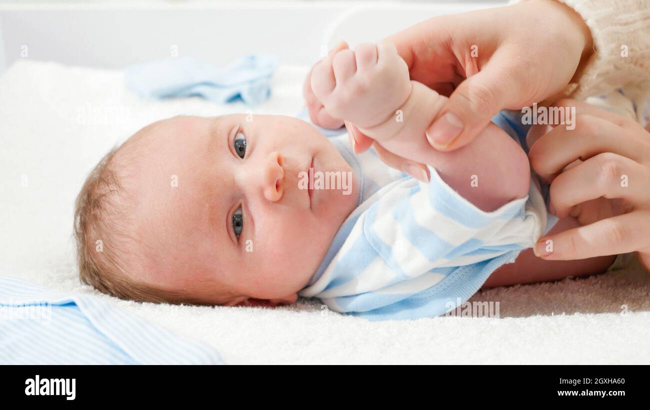 Portrait of little smiling newborn baby lying in crib and holding ...