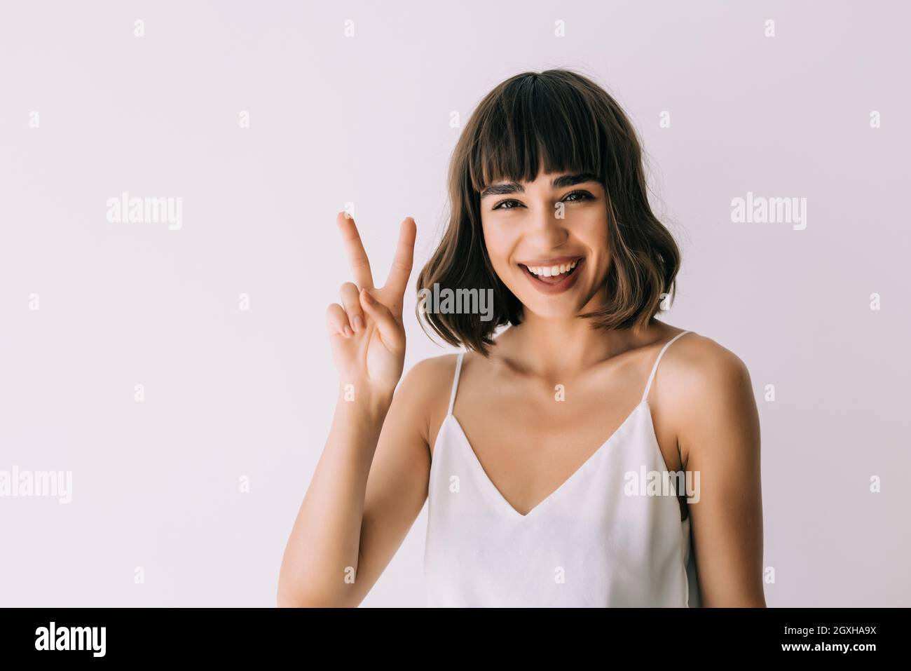 young woman showing V sign, isolated on white background Stock Photo ...