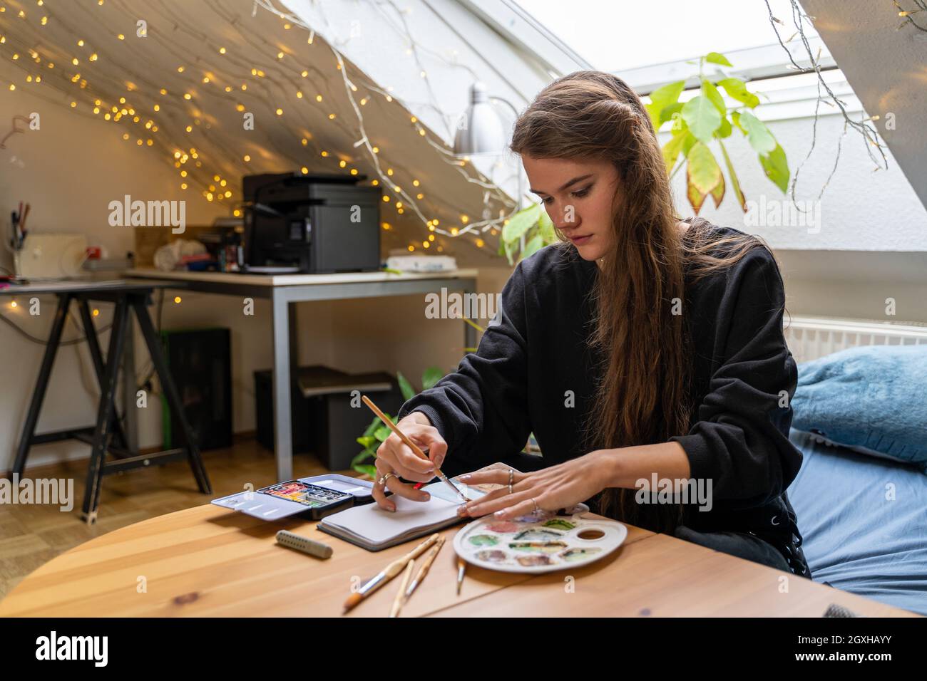 Brunette woman drawing nature landscape in paper notebook with ...